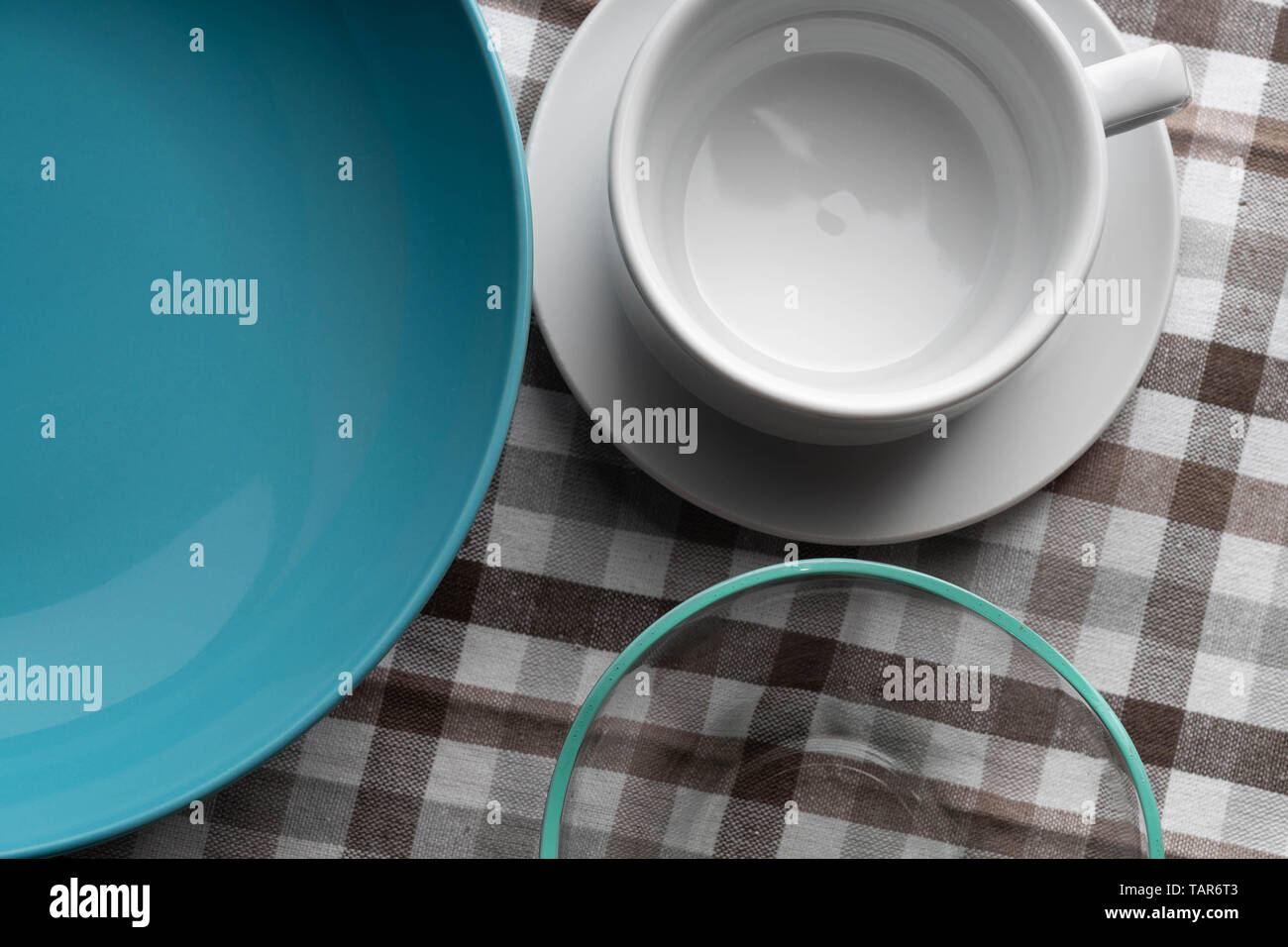 A white empty teacup, a blue plate and two ice-cream bowls are on the ...