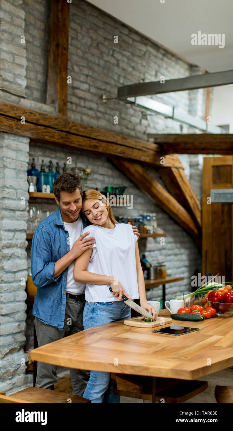 Lovely cheerful young couple cooking dinner together and having fun at ...