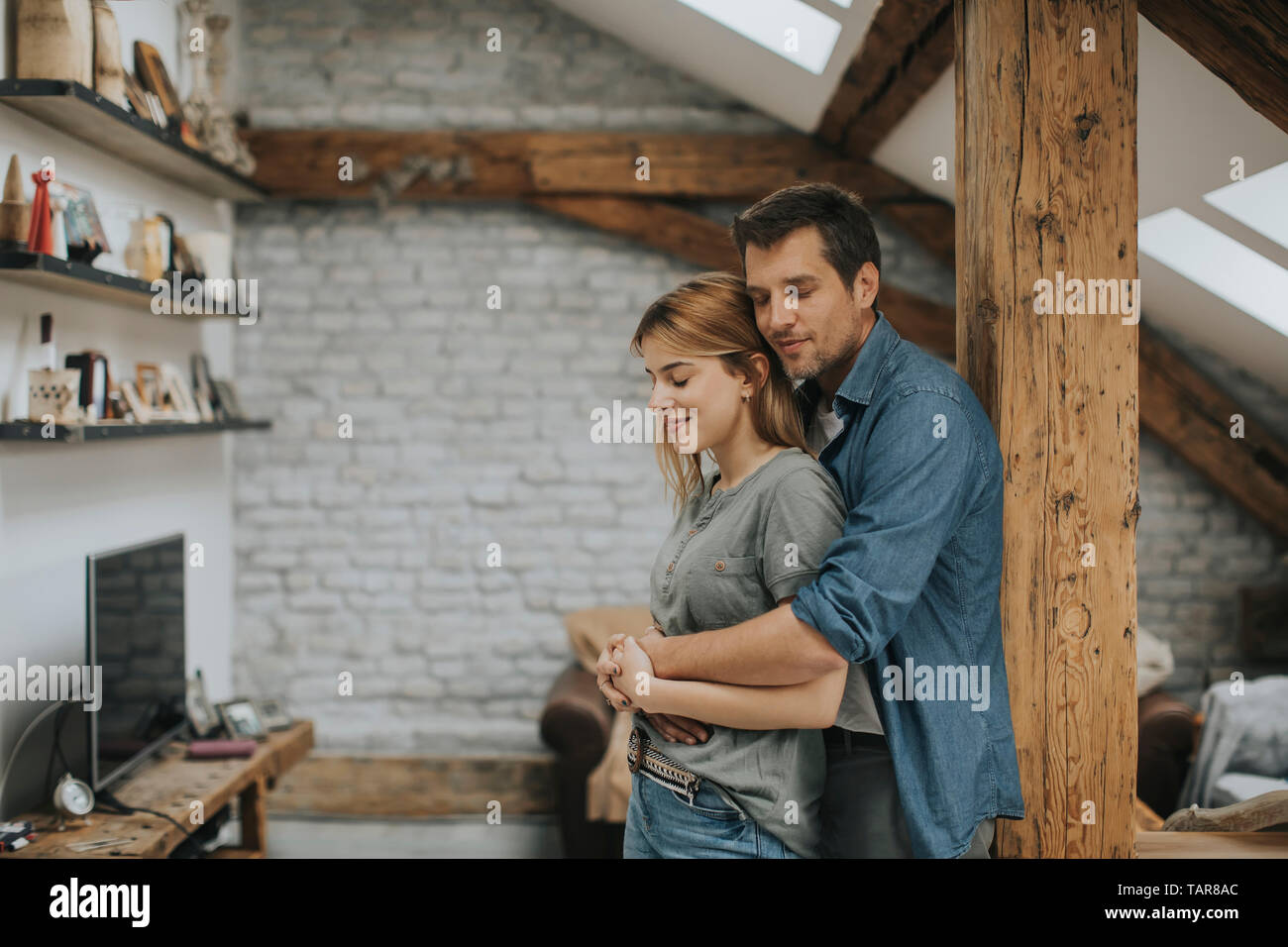 Young man and woman hugging standing at home interior and tender ...