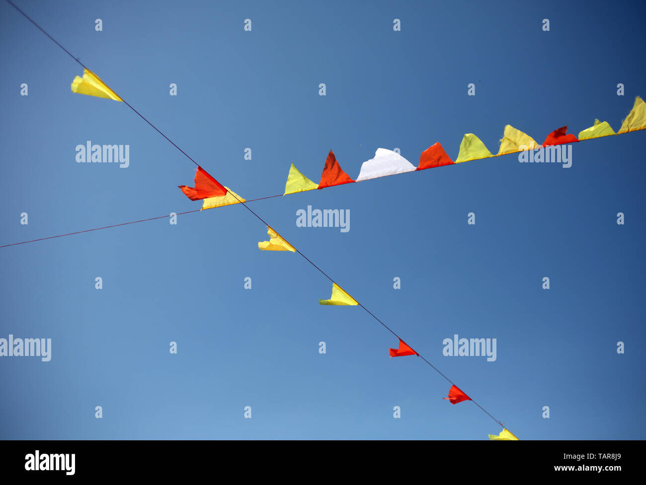 Colorful flags of the street festival, fair or party against blue sky ...