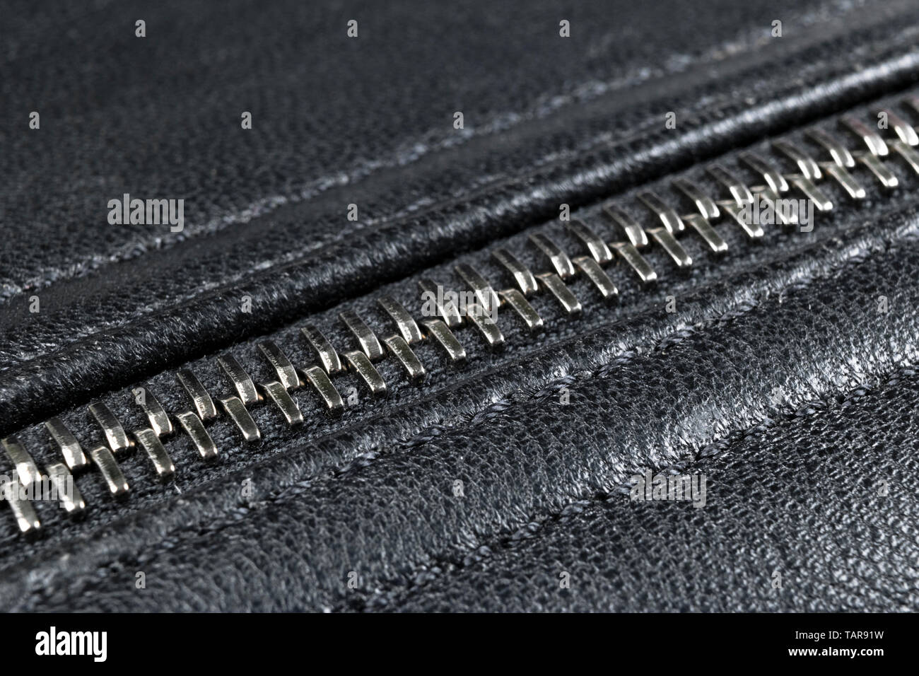 Macro shot of zipper on black leather texture background with stitching ...