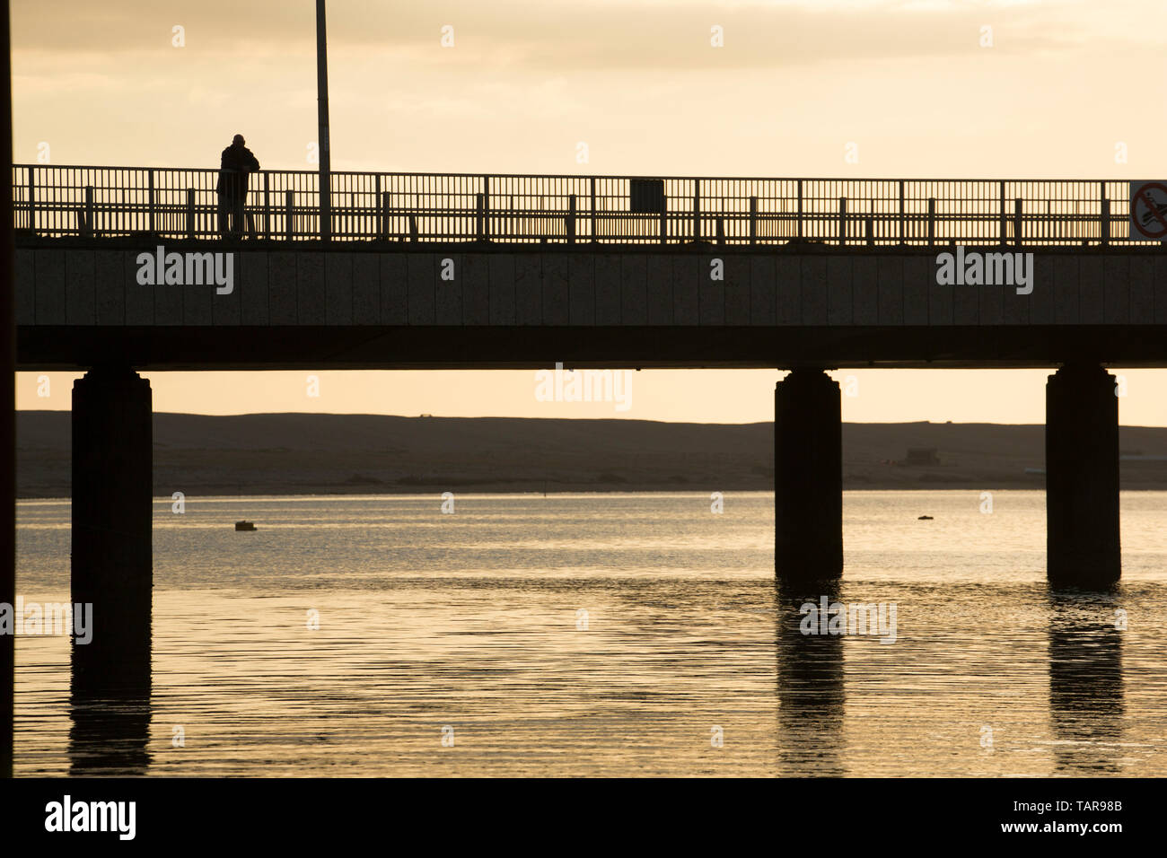 A man standing on the bridge at Ferry Bridge in the evening in May ...