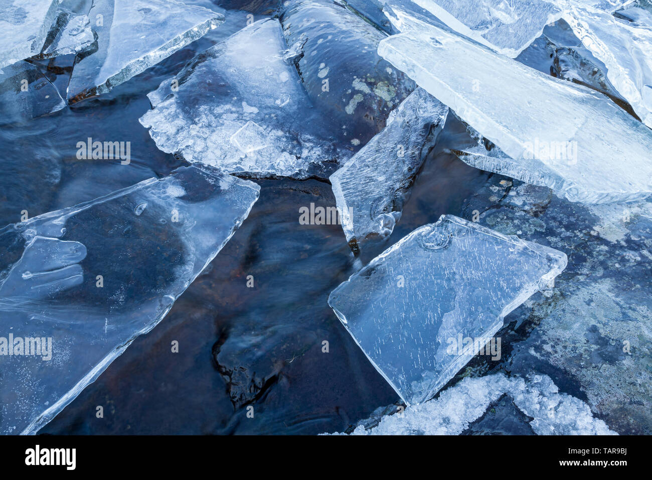 Pieces of ice on rock at lake shore Stock Photo - Alamy