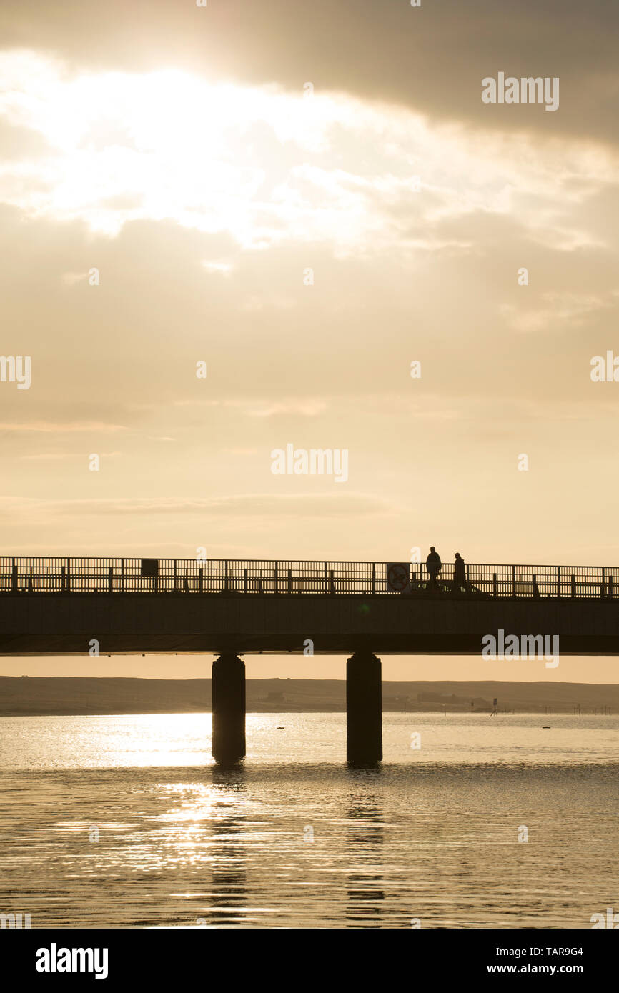 Two people crossing the bridge at Ferry Bridge Ferry in the evening in ...