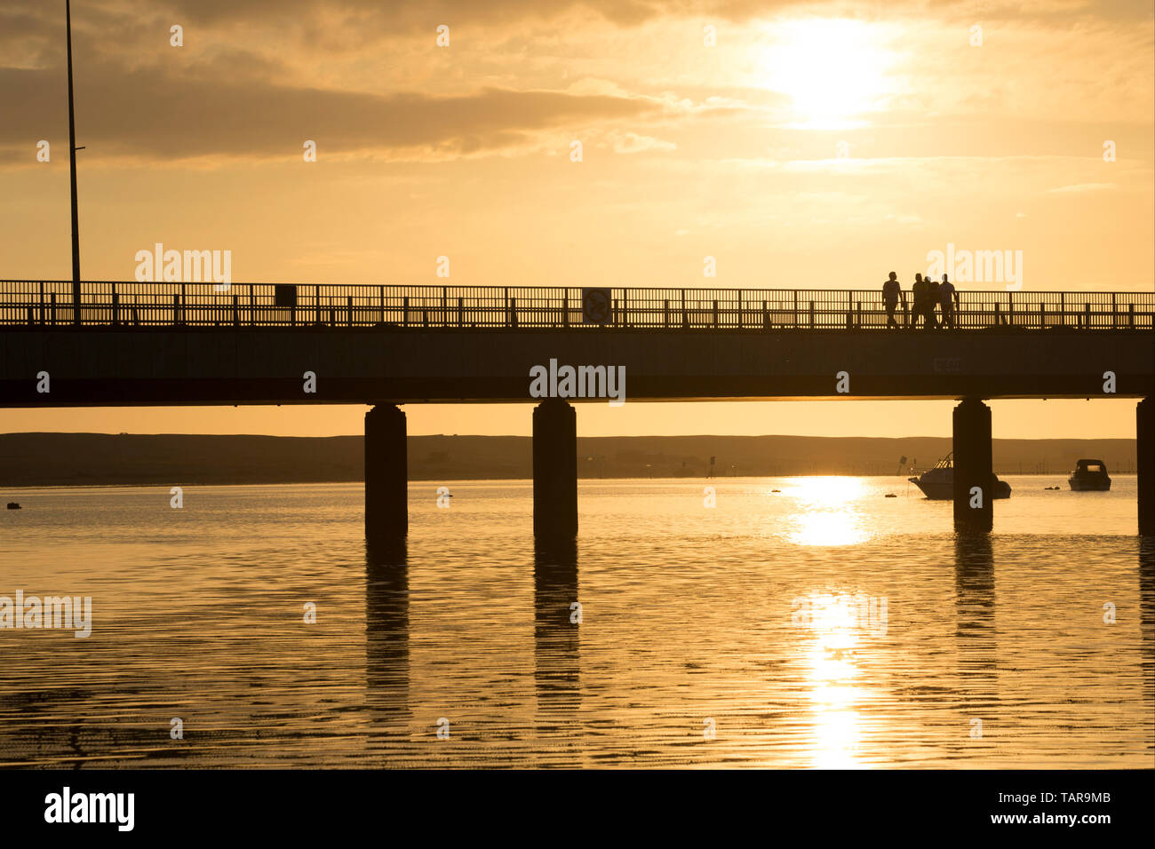 A group of people crossing the bridge at Ferry Bridge as the sun starts ...