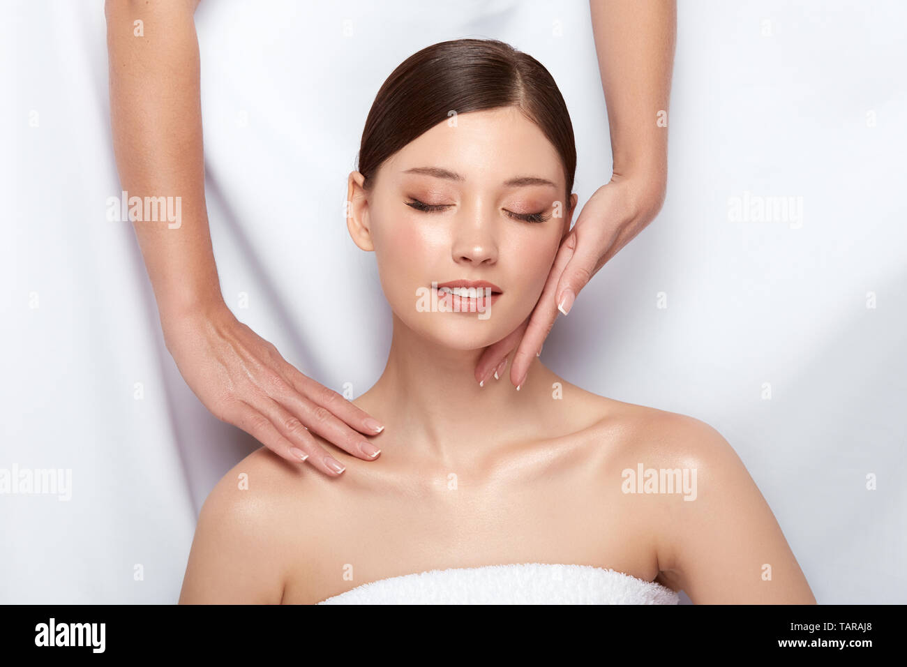 female hands doing massage for woman's face and shoulders, beautiful ...