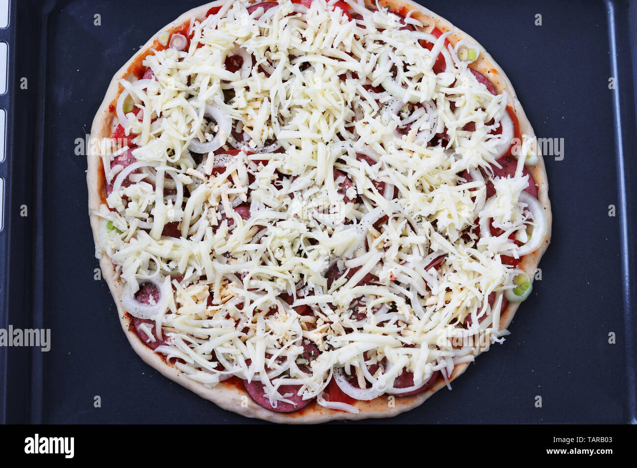 Semi-finished pizza before baking, location on a baking sheet, top view ...