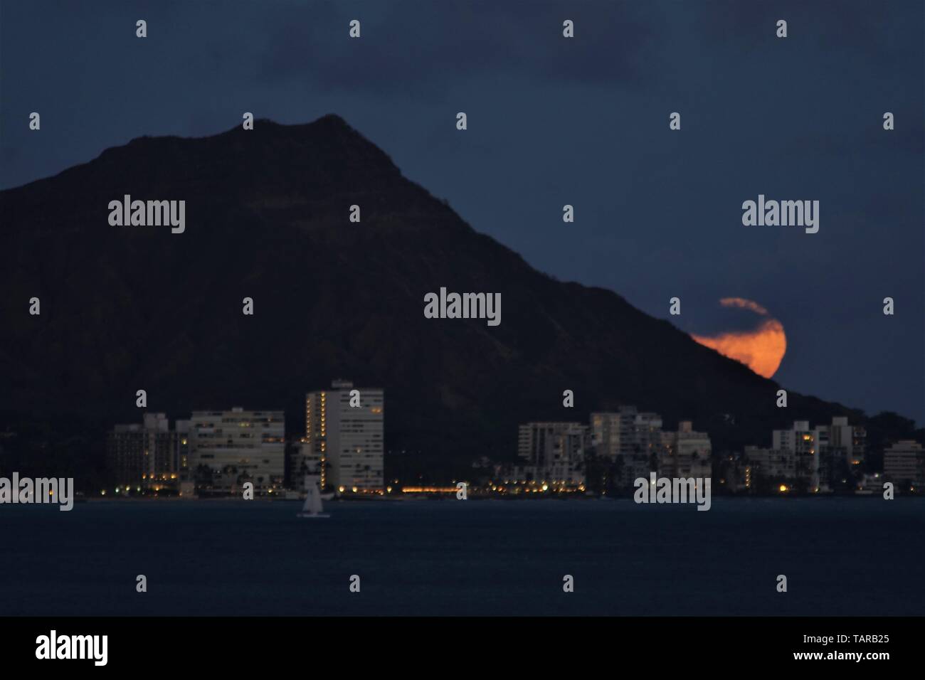A beautiful full moon glows orange as it rises above the famous Diamond ...