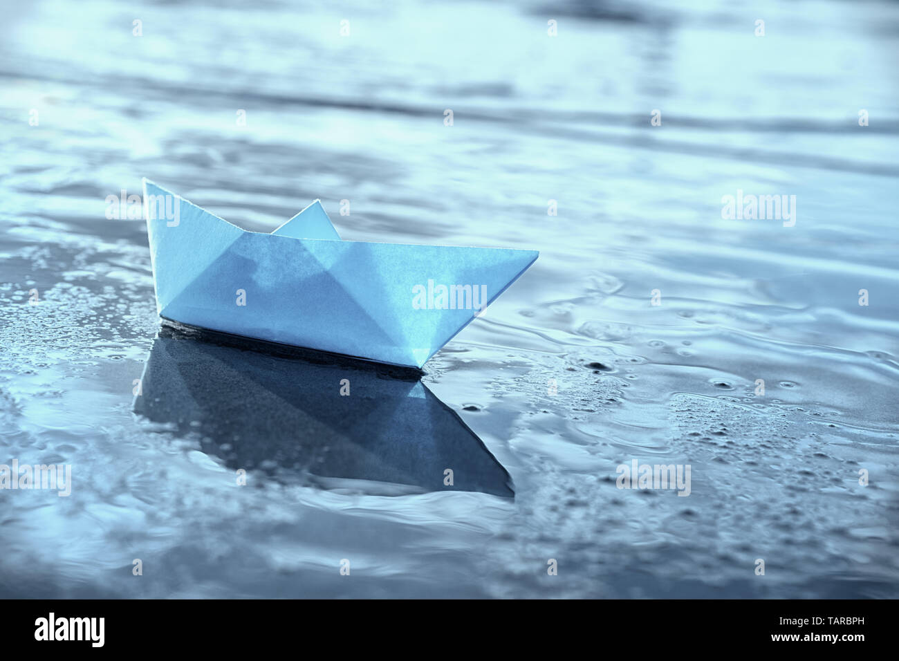 Lonely blue paper boat in shallow water. Blue toned image Stock Photo ...