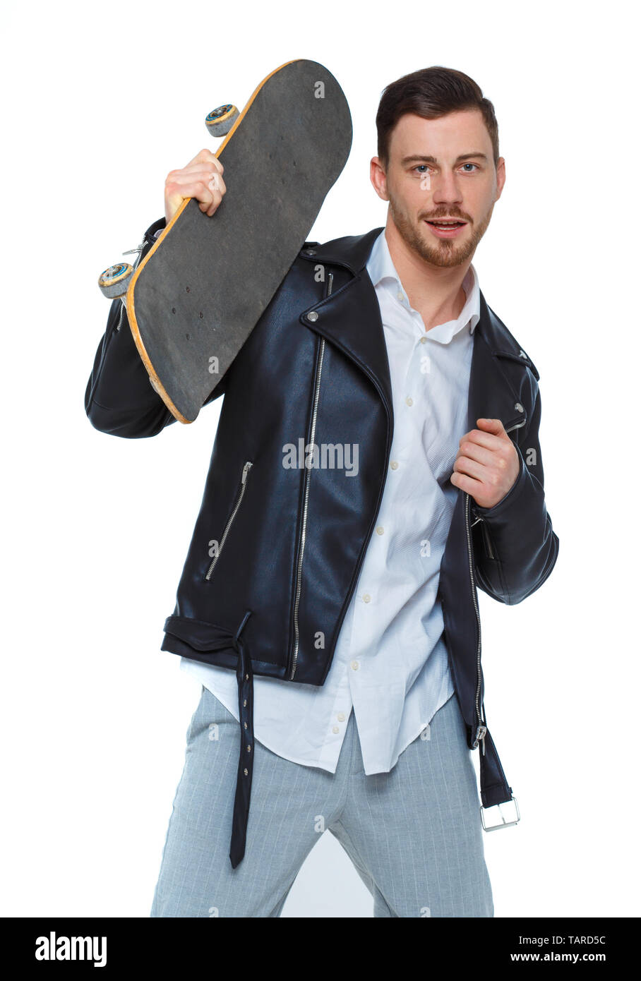 A man with a skateboard. A guy in stylish clothes and trousers posing ...