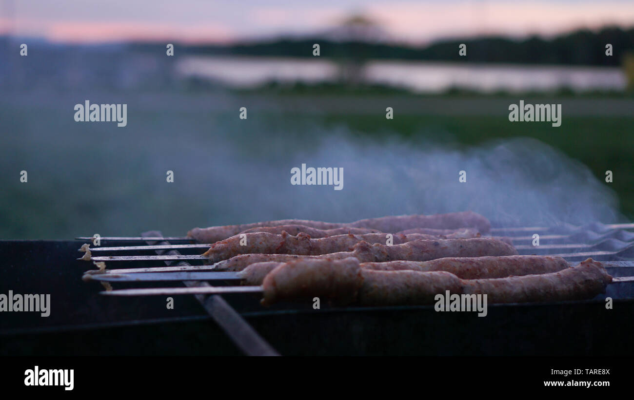 Grilling Sausages At Sunset Outdoors Gathering With Friends And Family grilling-sausages-at-sunset-outdoors-gathering-with-friends-and-family