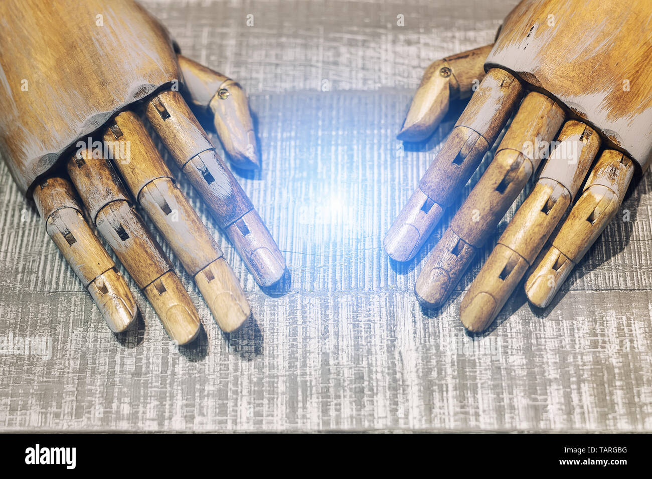 Close-up pair of wooden dummy hands and blue light between. Care about ...