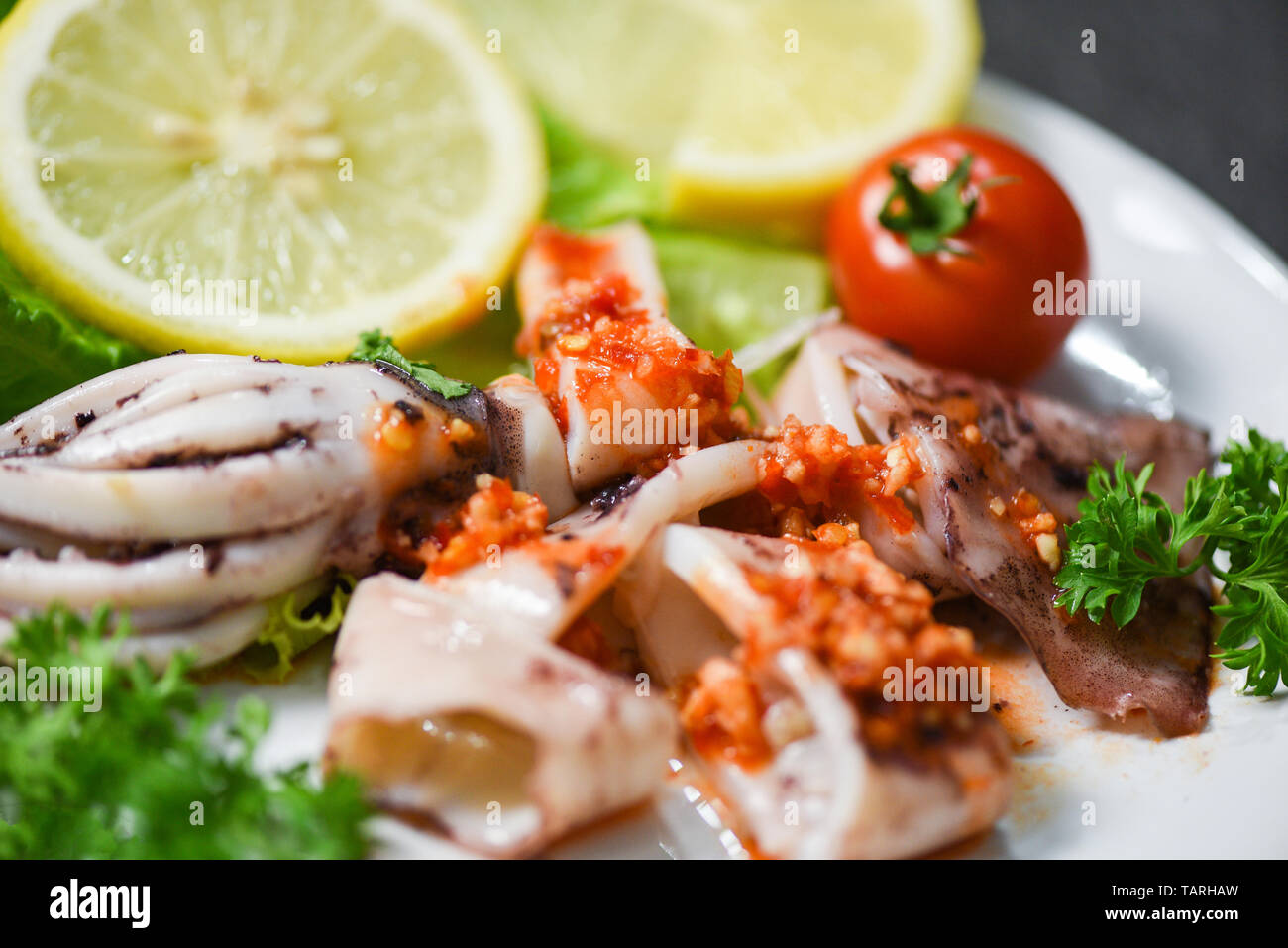 Squid salad with chilli sauce spicy herbs and spices / Grilled squid slice on plate in the ...