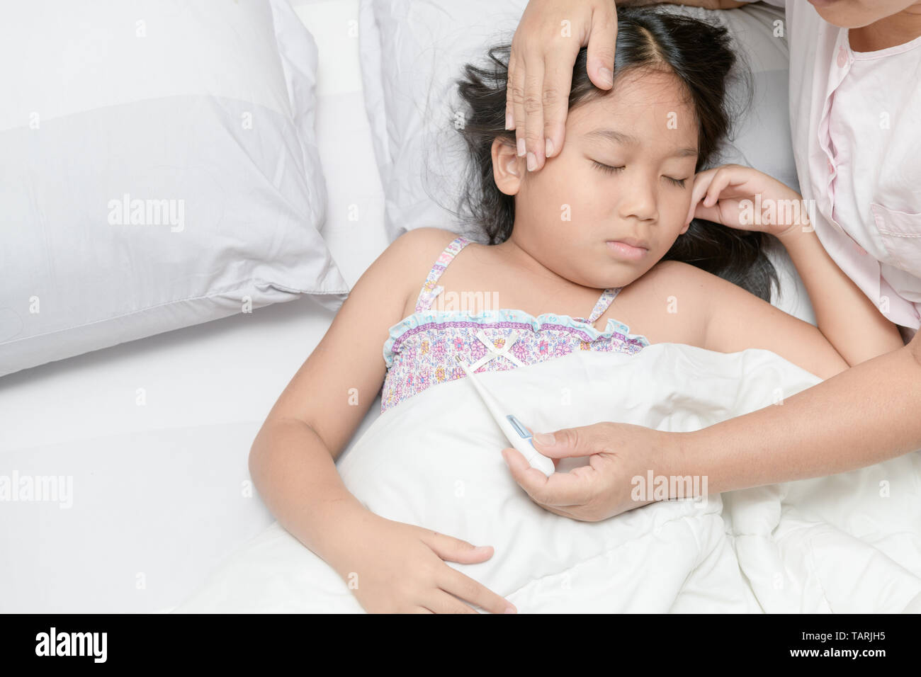 Mother measuring temperature of ill kid. Sick child with high fever laying in bed and mother ...