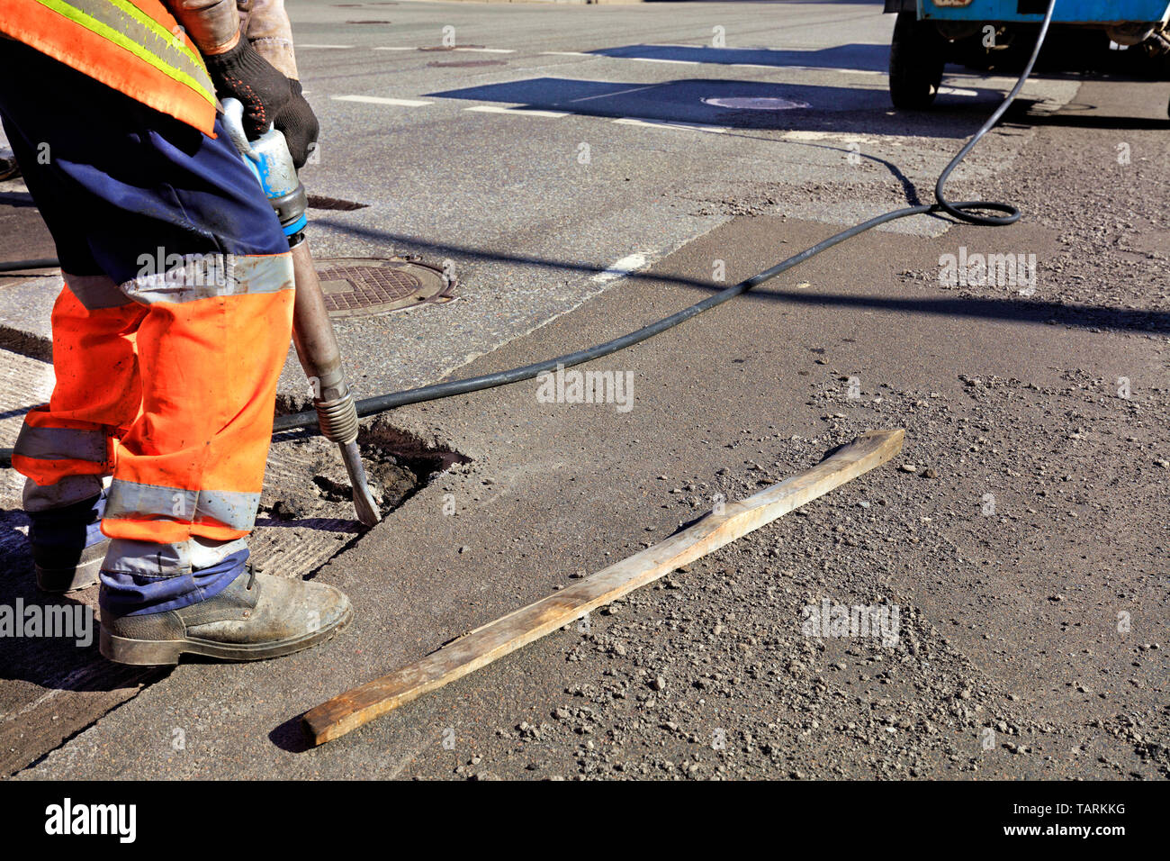 A road maintenance worker removes old asphalt on the roadway with a ...