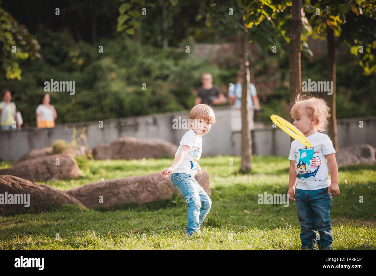 Chindren playing frisbee with son on meadow in park, summer day ...