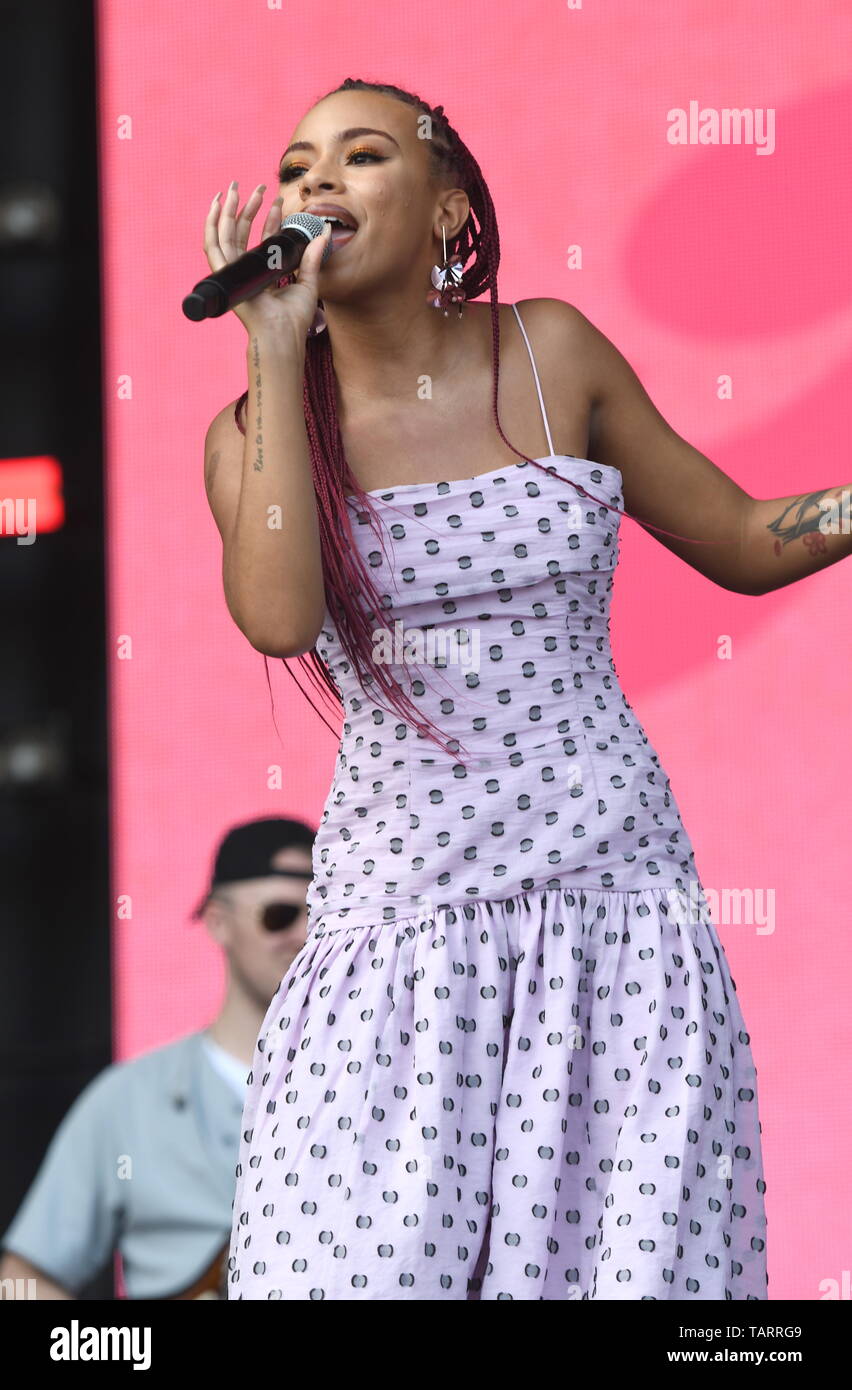 Singer Ravyn Lenae is shown performing on stage during a live concert ...