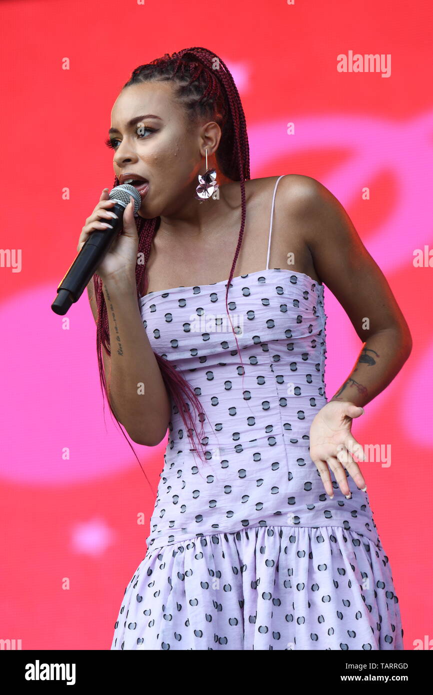 Singer Ravyn Lenae is shown performing on stage during a live concert ...