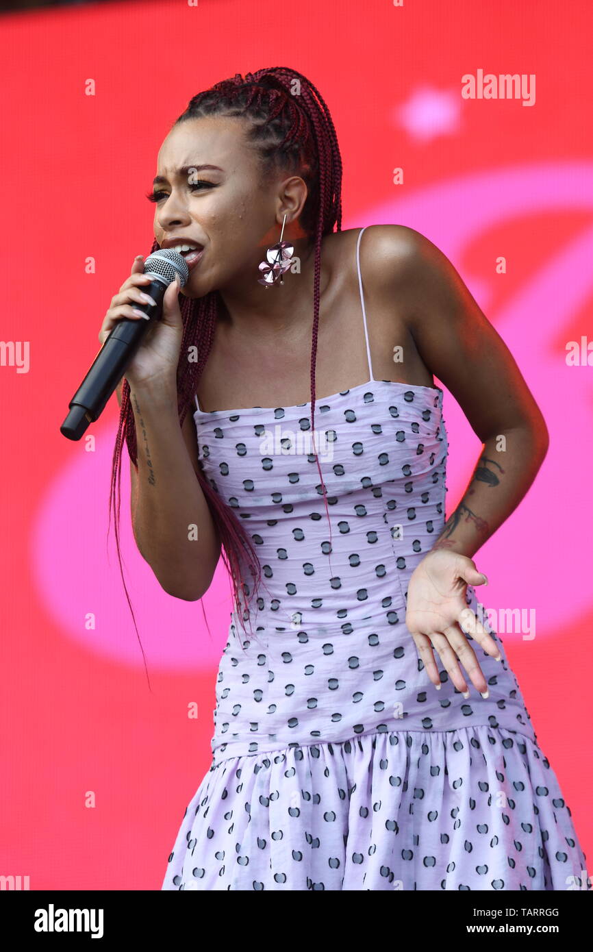 Singer Ravyn Lenae is shown performing on stage during a live concert ...