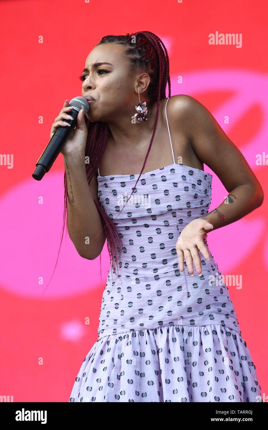 Singer Ravyn Lenae is shown performing on stage during a live concert ...