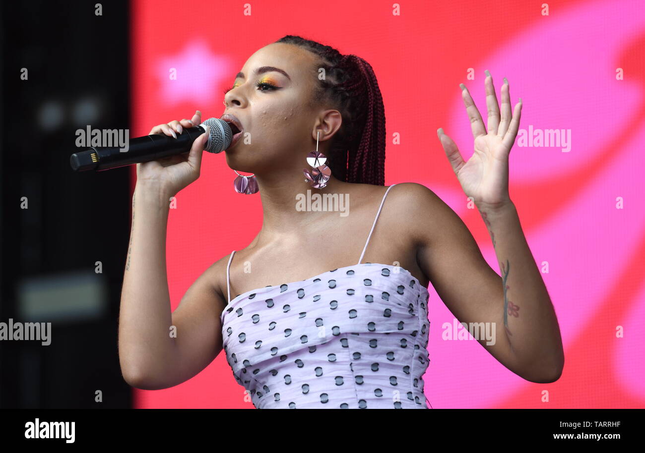Singer Ravyn Lenae is shown performing on stage during a live concert ...