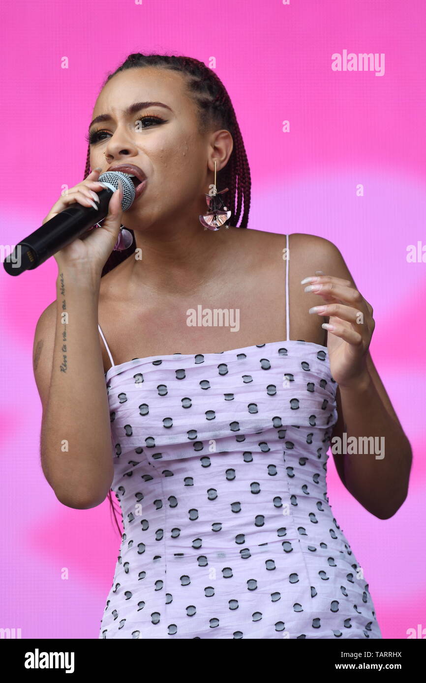 Singer Ravyn Lenae is shown performing on stage during a live concert ...