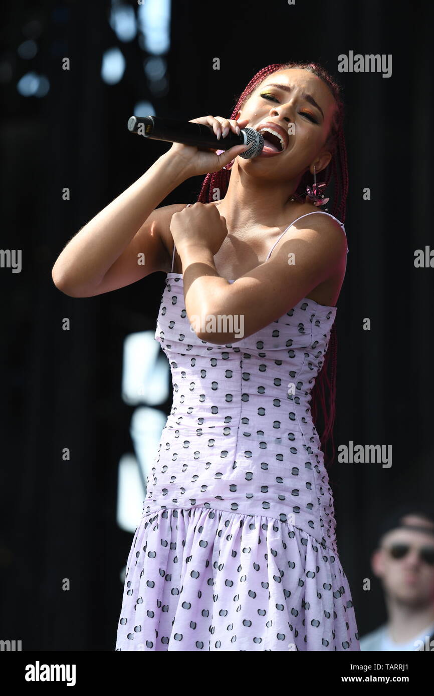 Singer Ravyn Lenae is shown performing on stage during a live concert ...