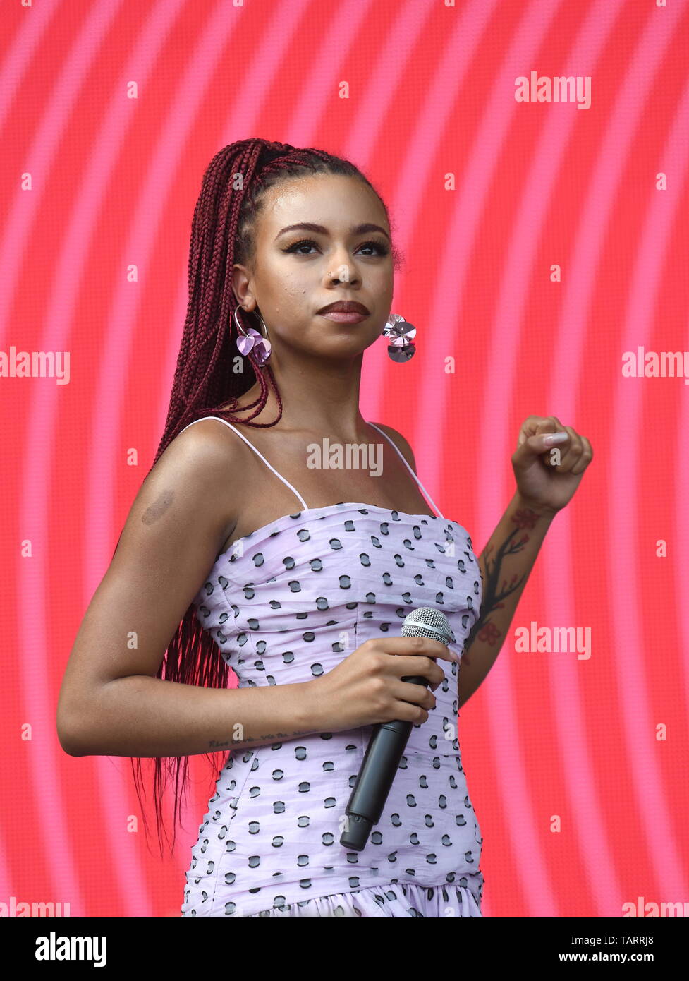 Singer Ravyn Lenae is shown performing on stage during a live concert ...