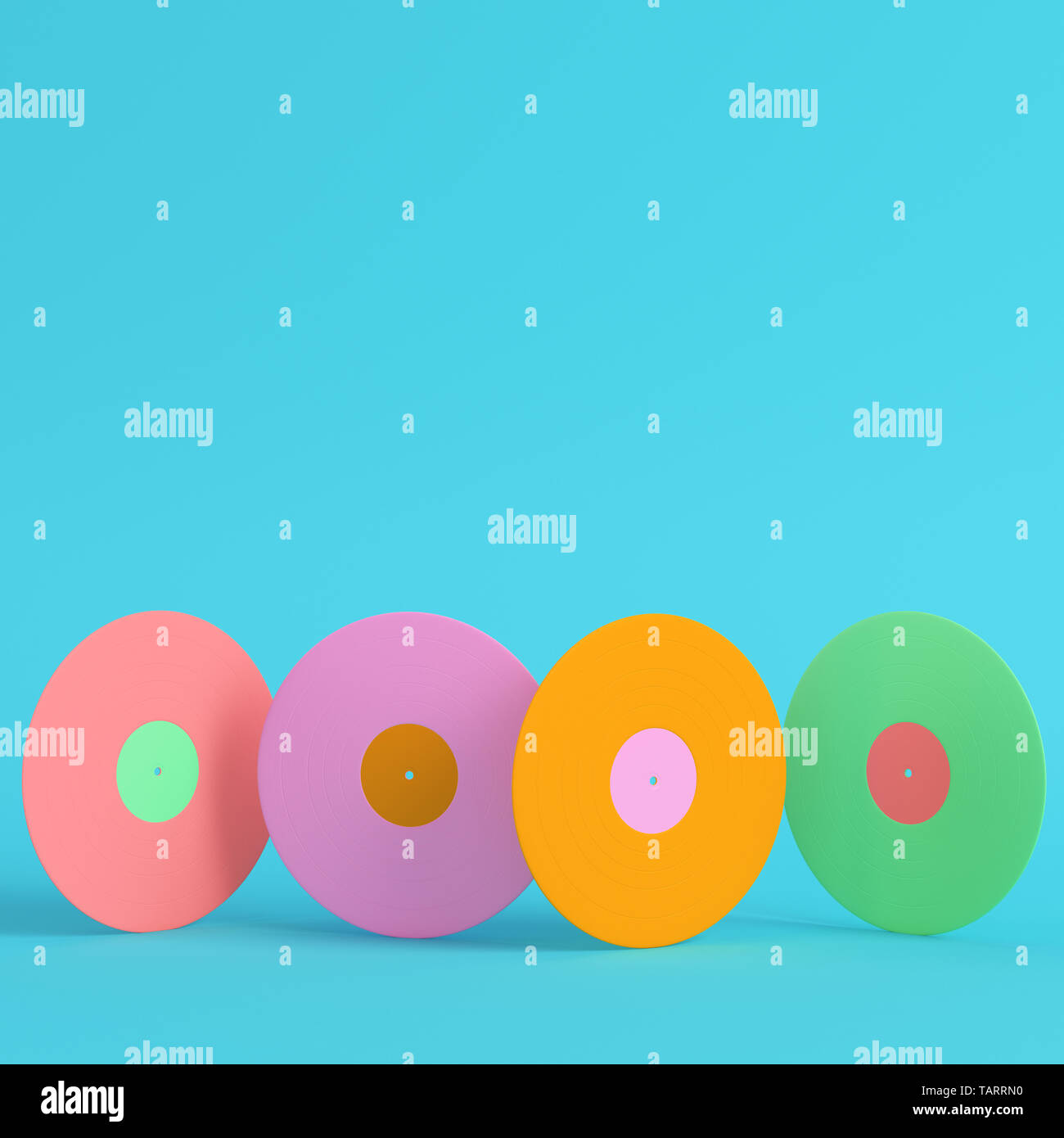 Four colorful vinyl records on bright blue background in pastel colors ...