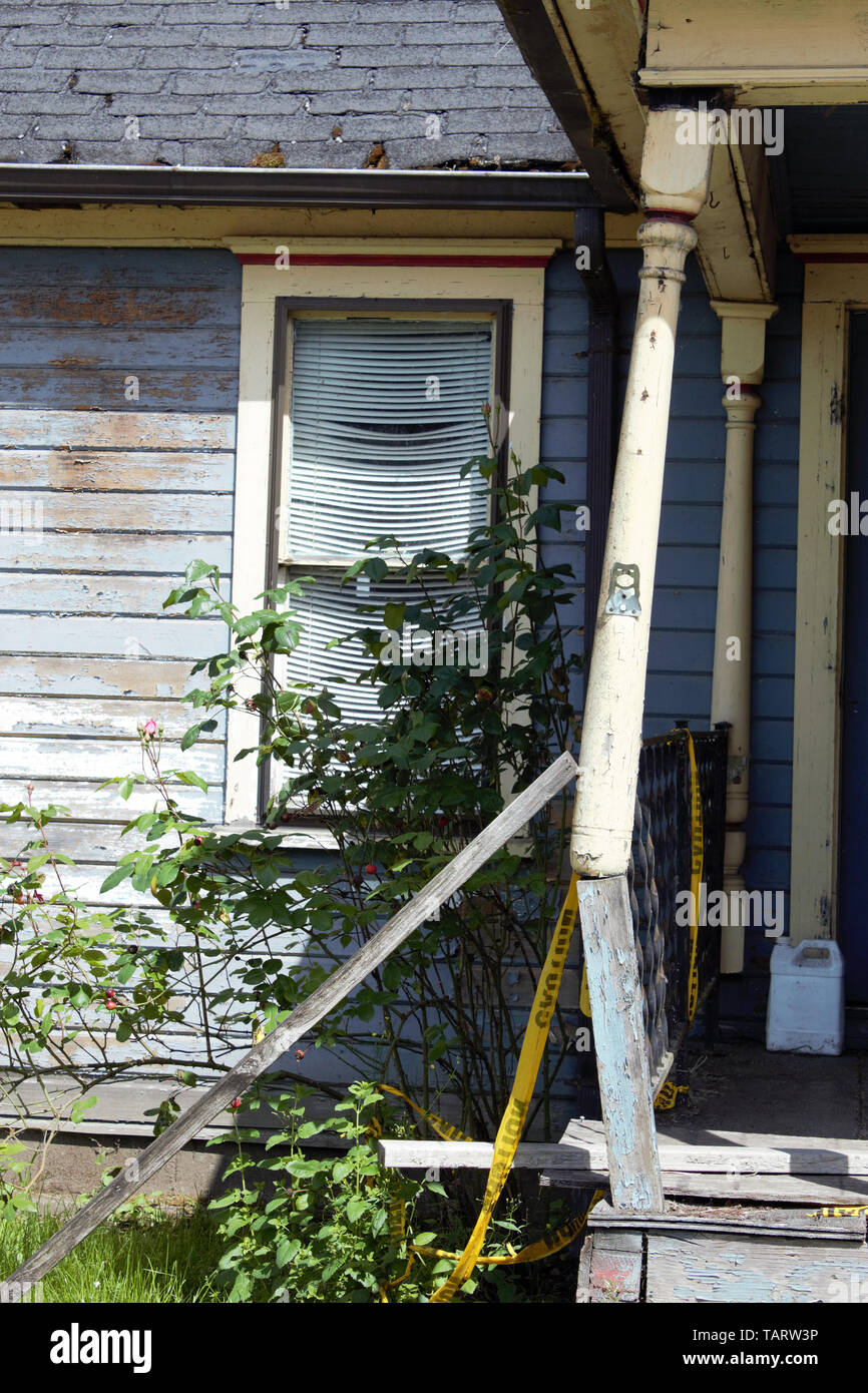 A broken porch post is precariously held in place by a wood brace Stock ...