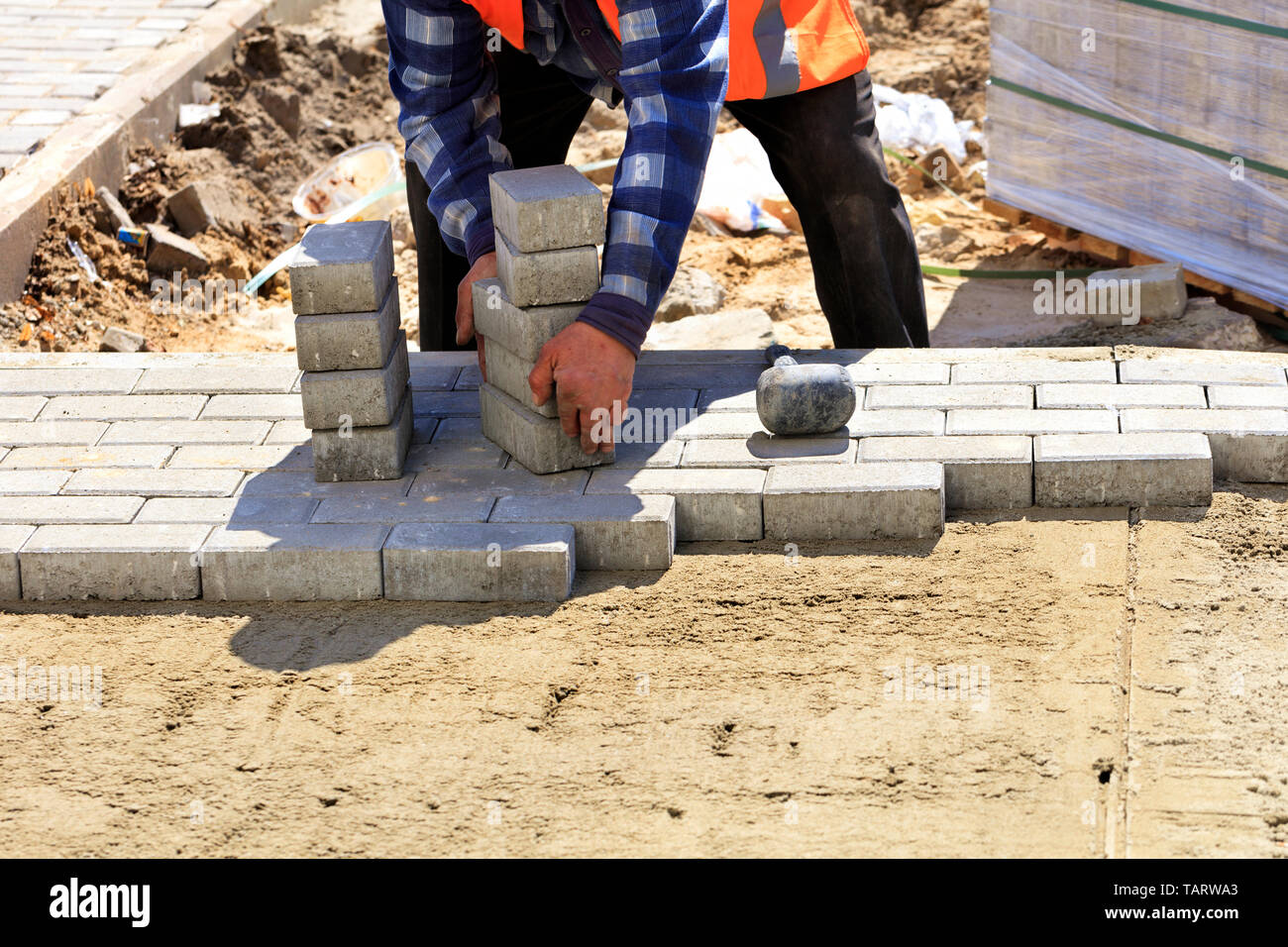 Worker brings a stack of paving slabs to lay it on the prepared flat ...