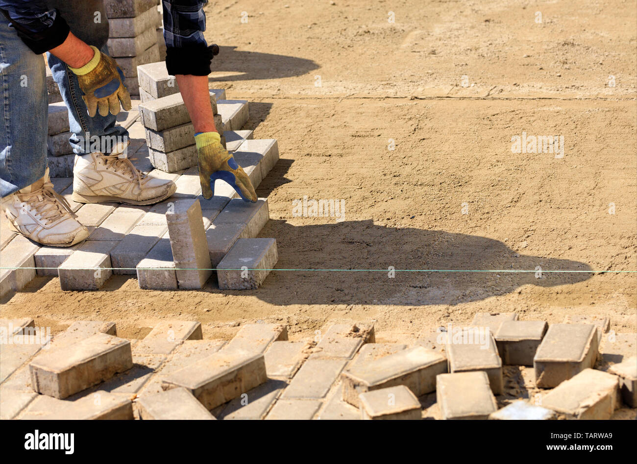 The worker puts the paving slabs along the stretched thread on the ...