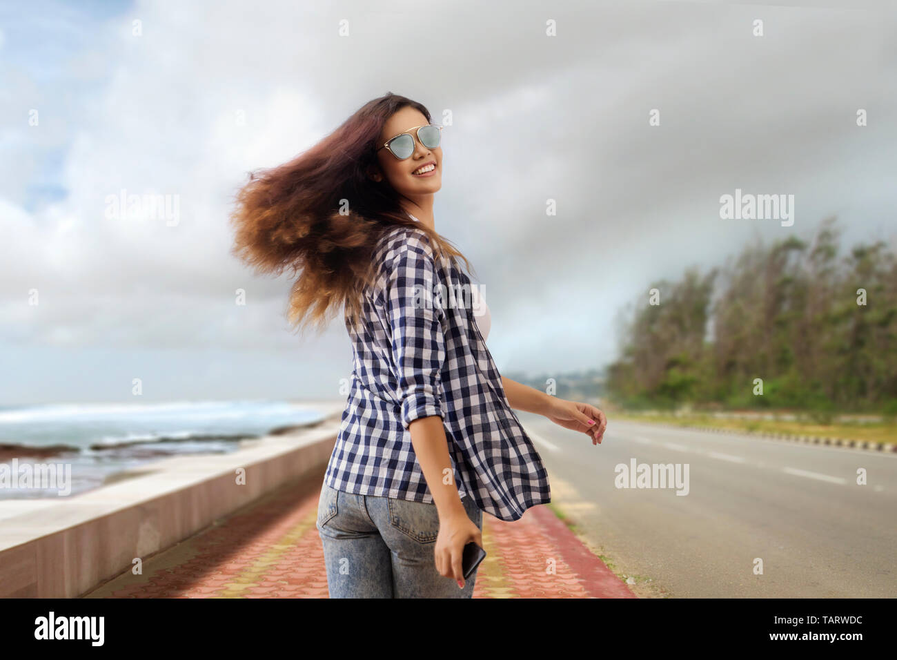 Woman looking back while walking on road beside sea Stock Photo - Alamy