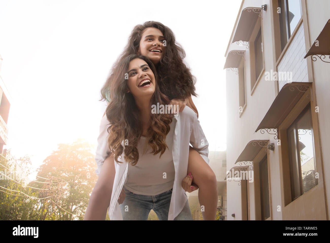 Woman carrying friend on her back walking outdoors in a street Stock ...