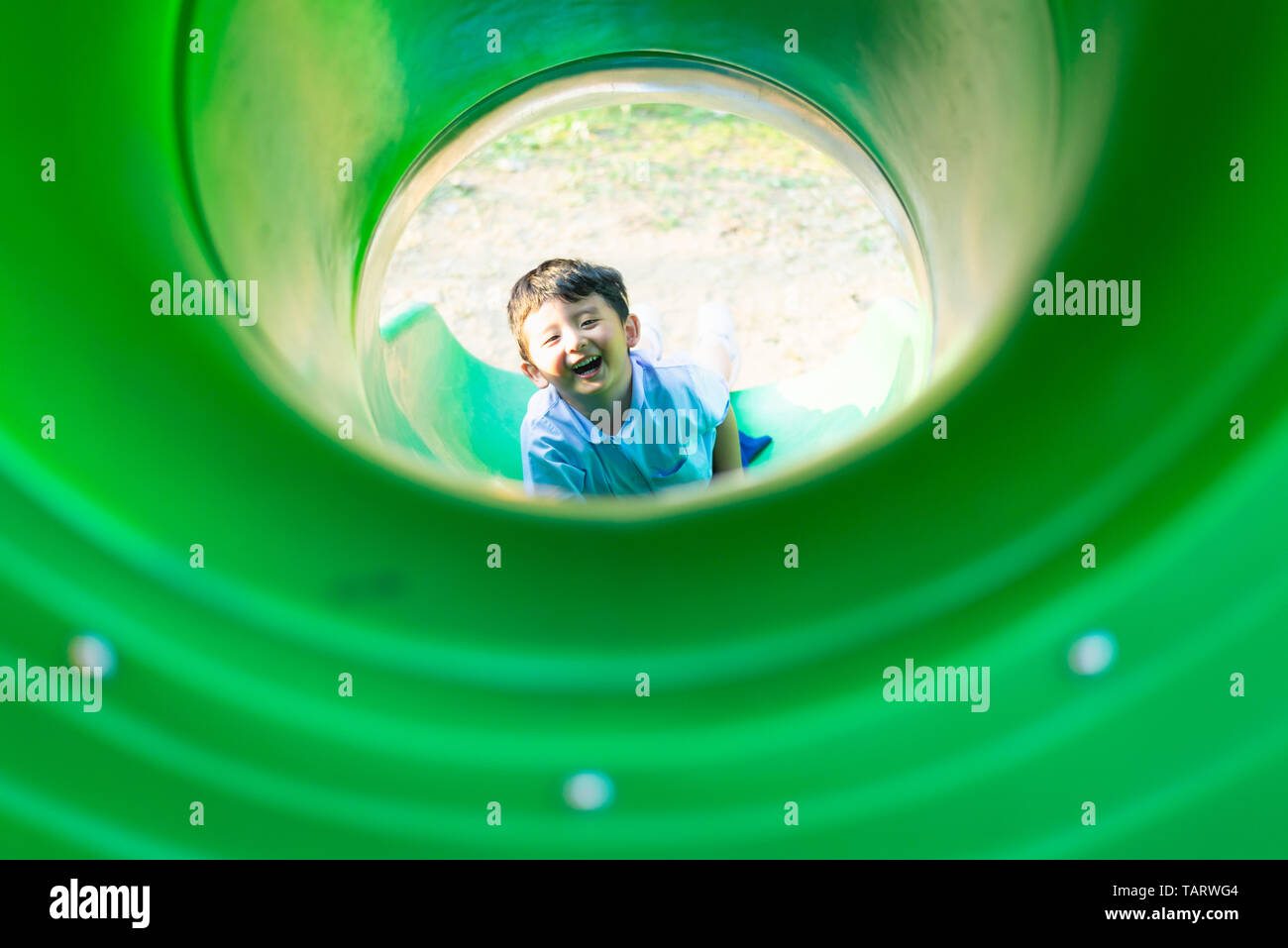 Little Asian kid climbing up the slide at the playground under the ...