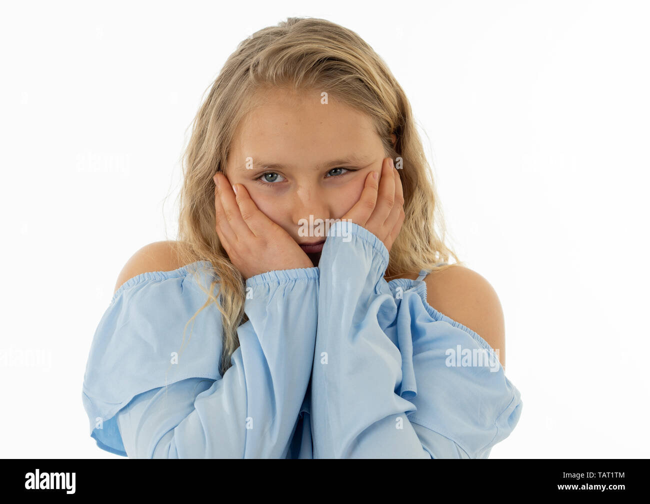 Close up portrait of a cute young shy girl looking timid at the camera ...