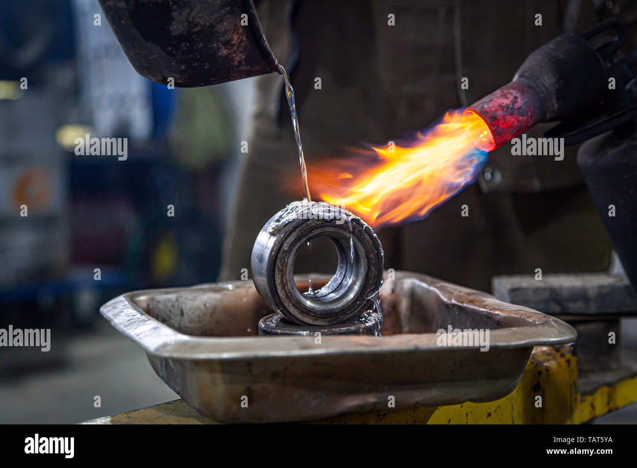 Close-up male welder welds metal using a gas burner and poured lead ...