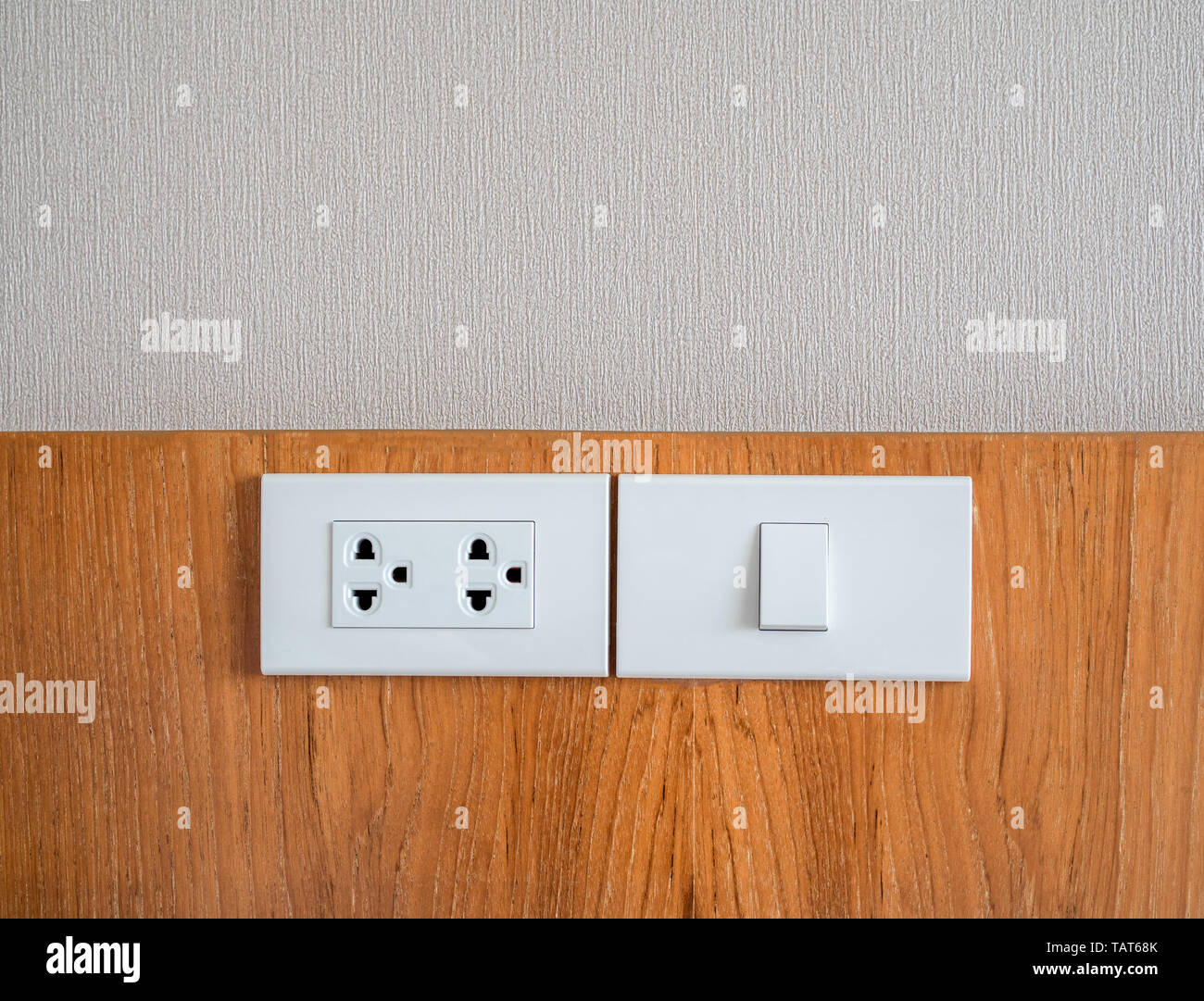 White electrical socket and white light switch on wooden and wall ...