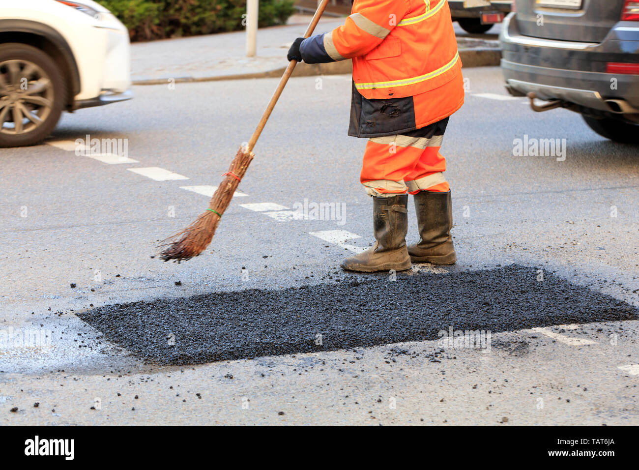 The road worker sweeps with a panicle away with fresh asphalt on the ...