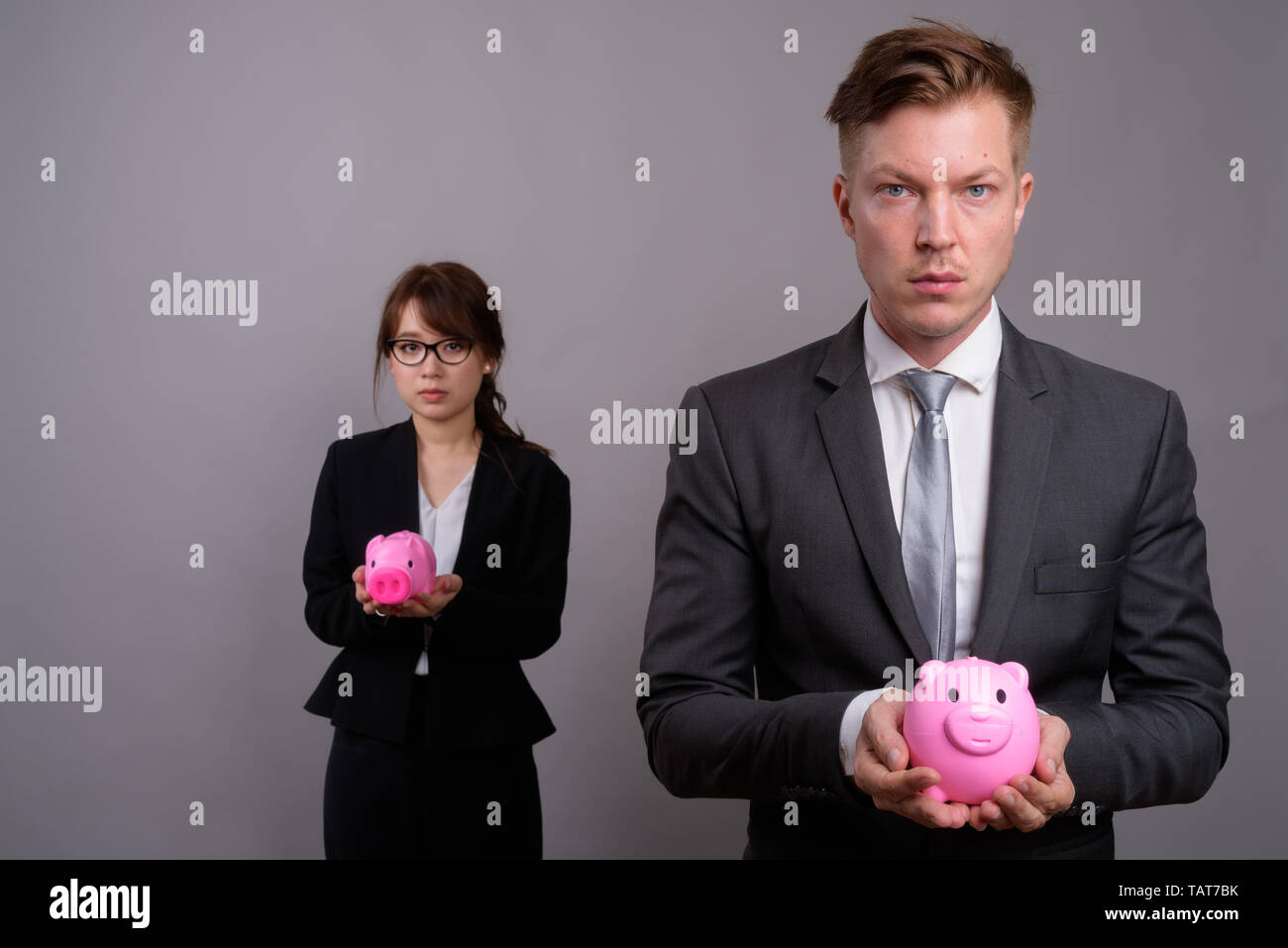 Young businessman and young Asian businesswoman against gray bac Stock ...