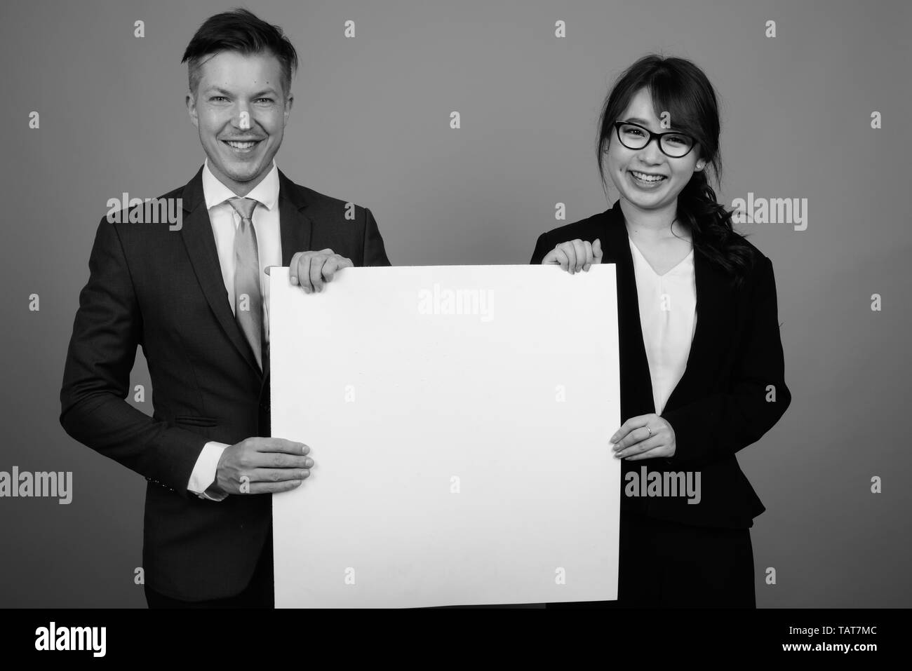 Young businessman and young Asian businesswoman against gray bac Stock ...