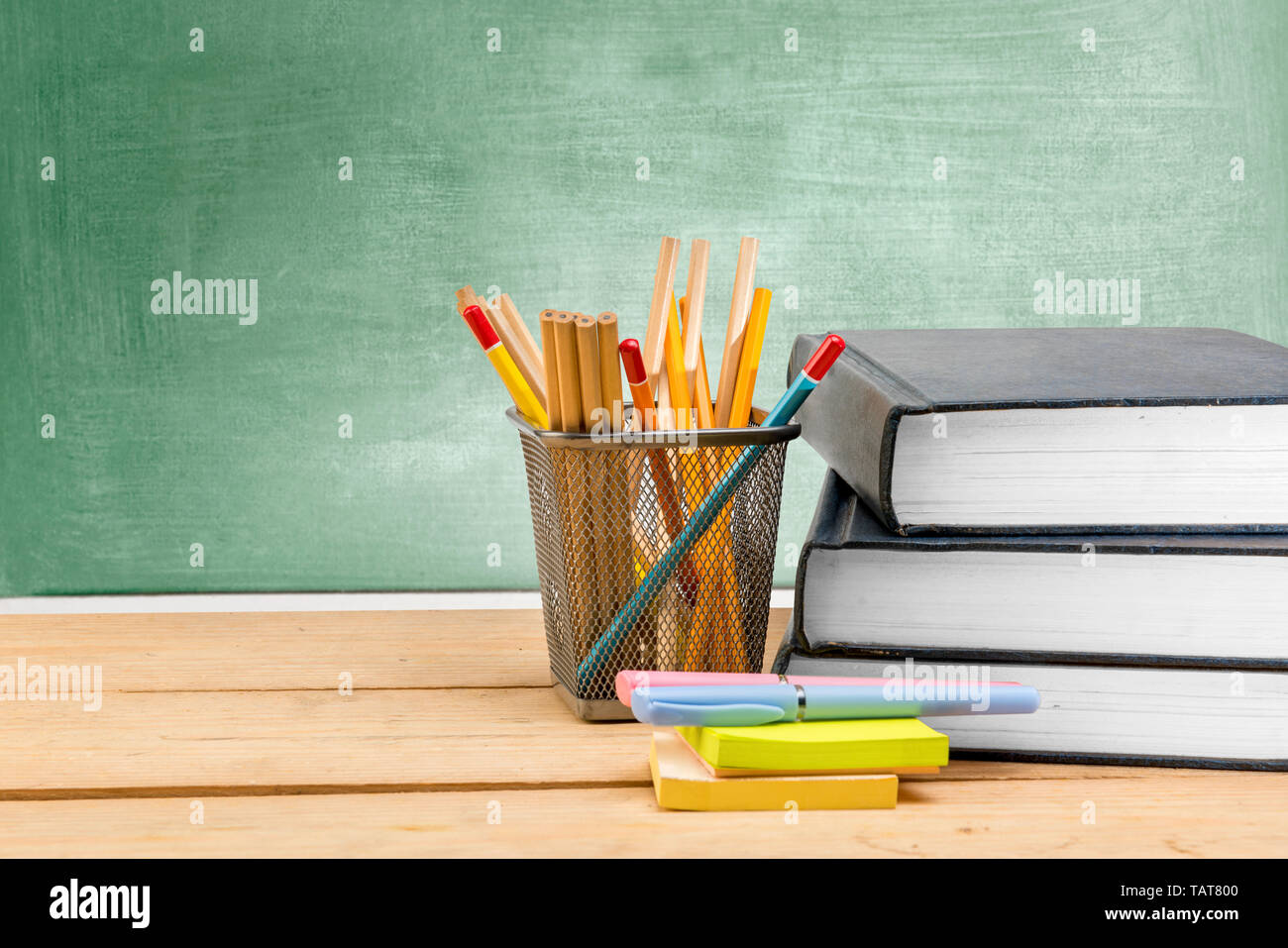 Pile of books with notes paper and pen with pencils in basket container ...