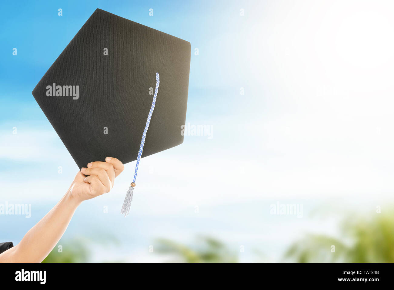Hand holding graduation hat with blue sky background. Graduation ...