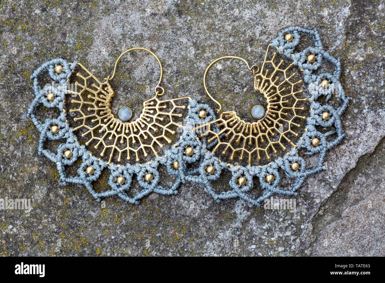 Metal macrame earrings on rocky background Stock Photo - Alamy