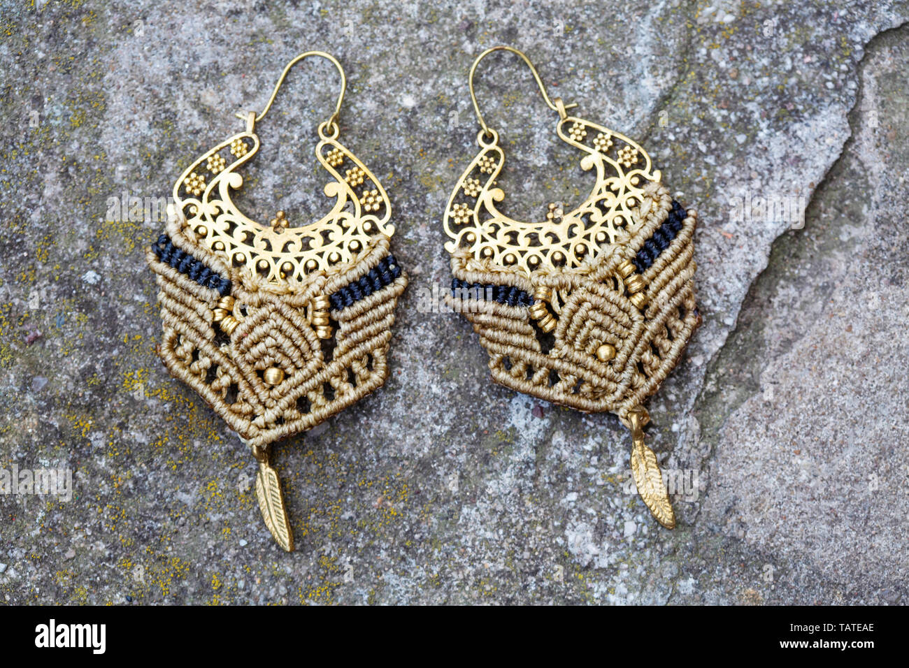 Metal macrame earrings on rocky background Stock Photo - Alamy
