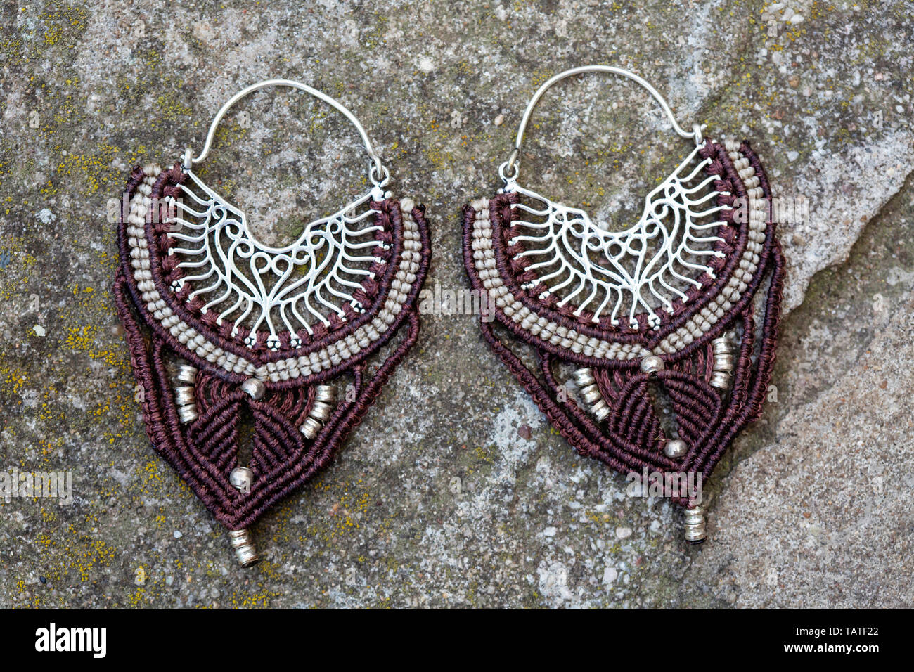 Metal macrame earrings on rocky background Stock Photo - Alamy