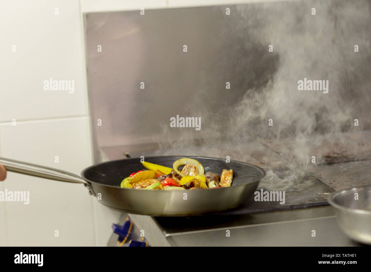 Chef frying vegetables on the gas stove with fire at the kitchen Stock ...