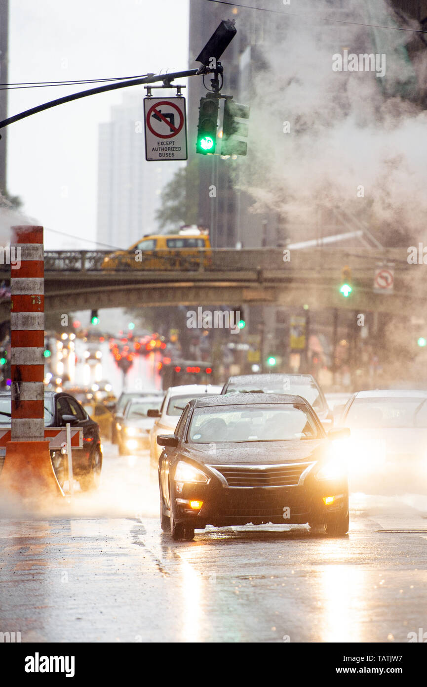 Some cars are crossing the 42nd street in Manhattan while steam coming ...