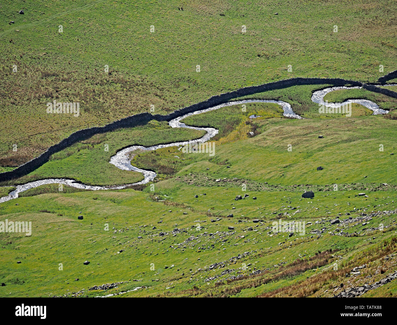 Meandering glittering stream winding along glacial valley alongside dry ...