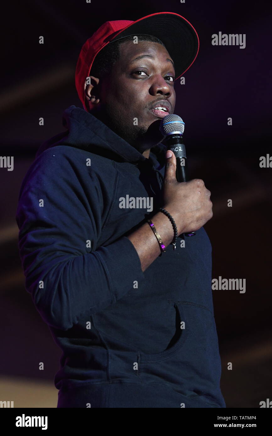 Comedian Michael Che is shown performing on stage during a "live" stand ...